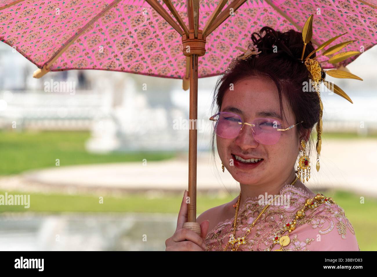 A young Thai woman dressed in traditional Thai dress at the Wat Rong Khun,(White Temple). Wat ...