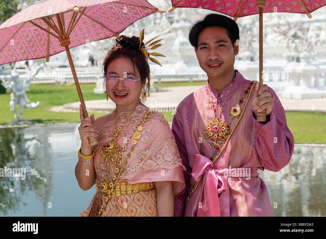 A young Thai couple dressed in traditional Thai dress at the Wat Rong Khun,(White Temple). Wat ...