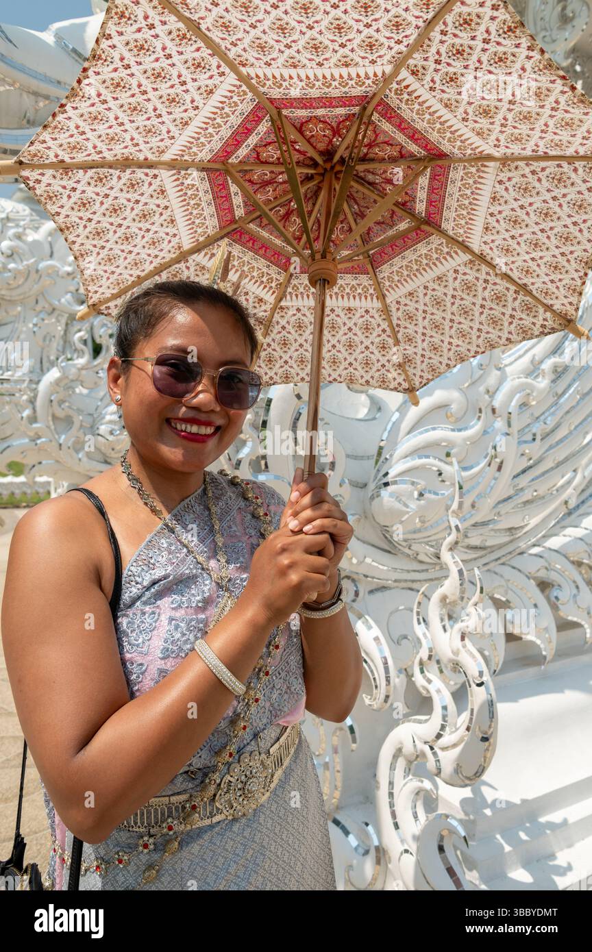 A young Thai woman dressed in traditional Thai dress at the Wat Rong Khun,(White Temple). Wat ...