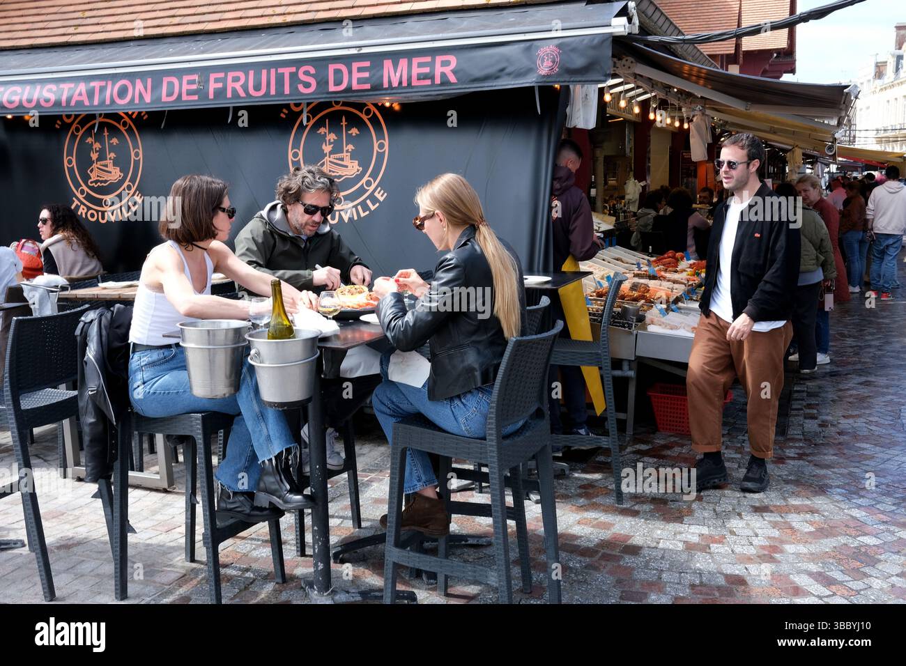 Visitors eating at fish market restaurants in Trouville in Normandy ...