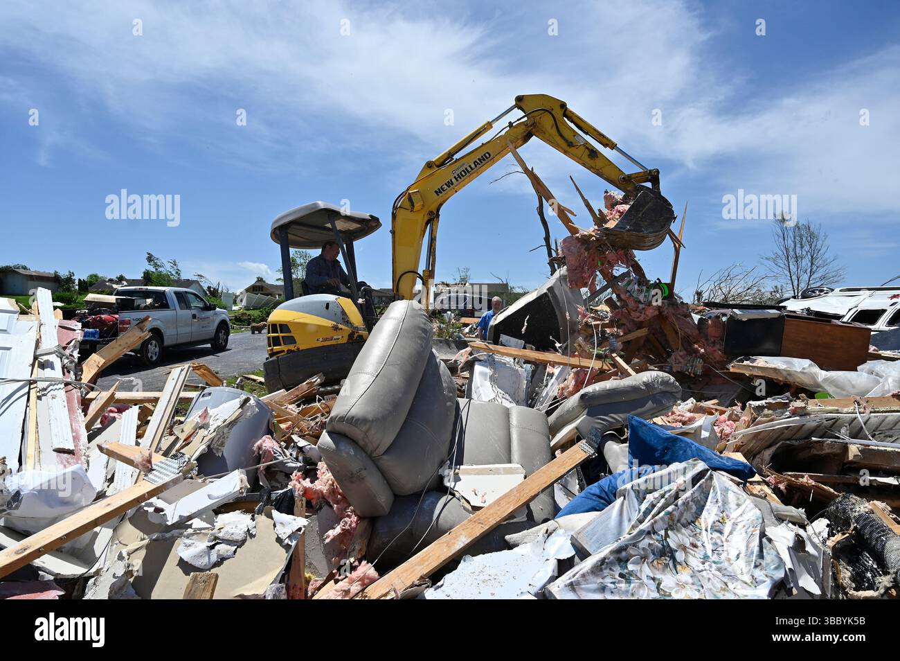 A man uses a back hoe to move debris into a pile following severe ...