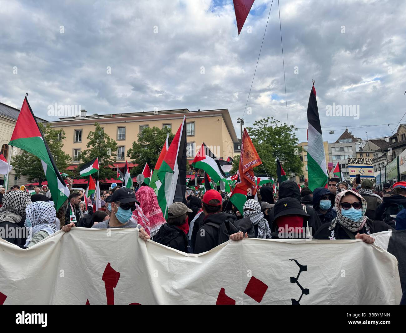 Basel, Switzerland. 17th May, 2025. People hold banners and flags ...
