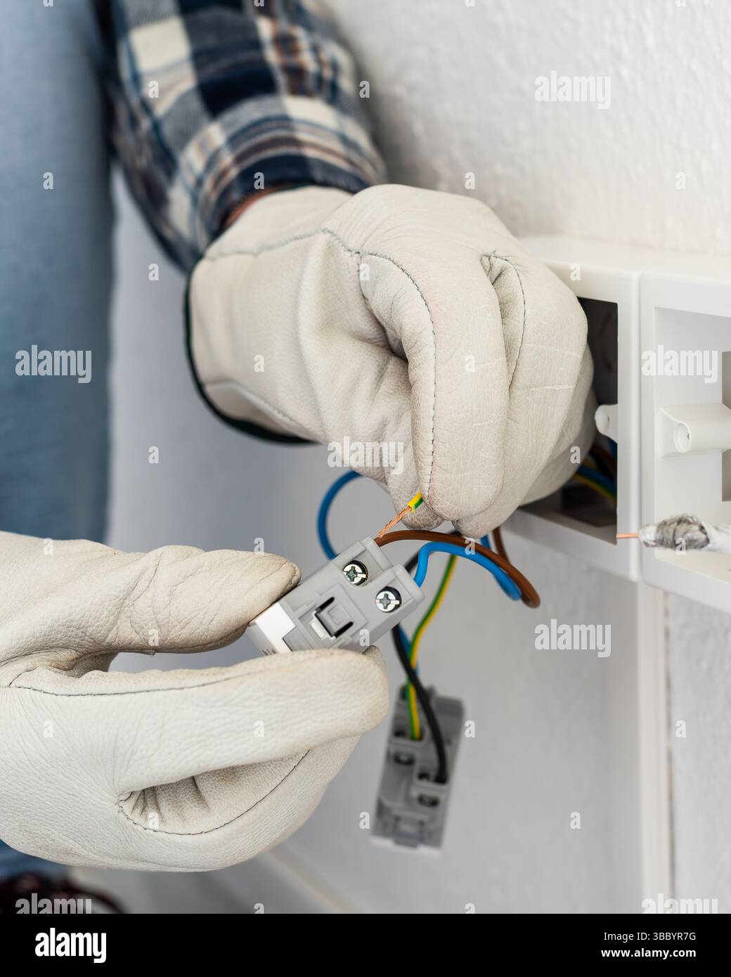 Electrician worker inserts electrical cables into the socket terminals ...