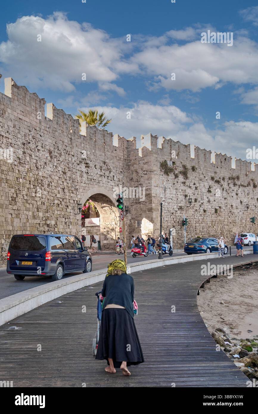 Crete.Greece - may 17, 2025: An elderly woman with a cart strolls along ...