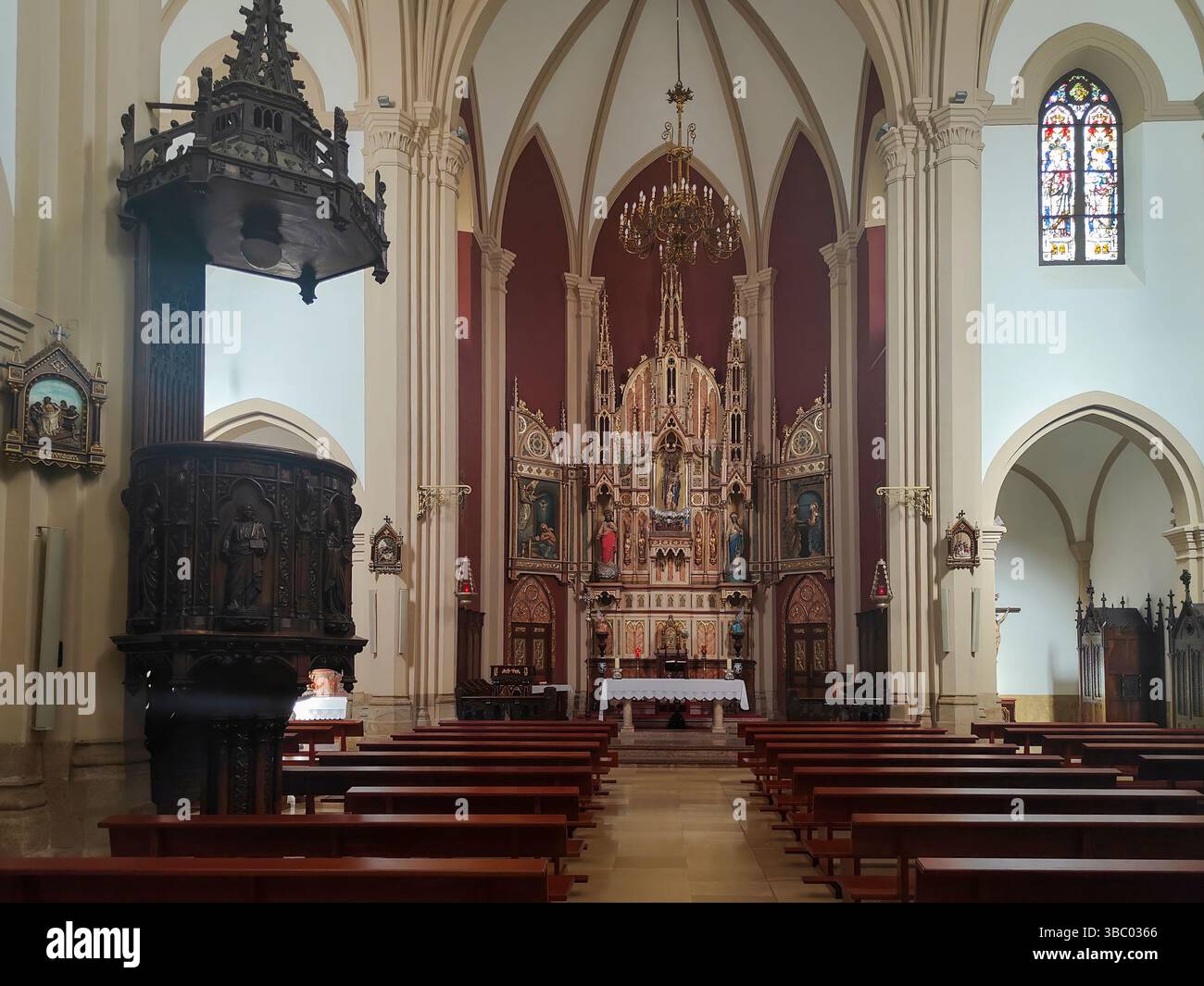 Ornate wooden pulpit and altar inside a catholic church with empty pews ...