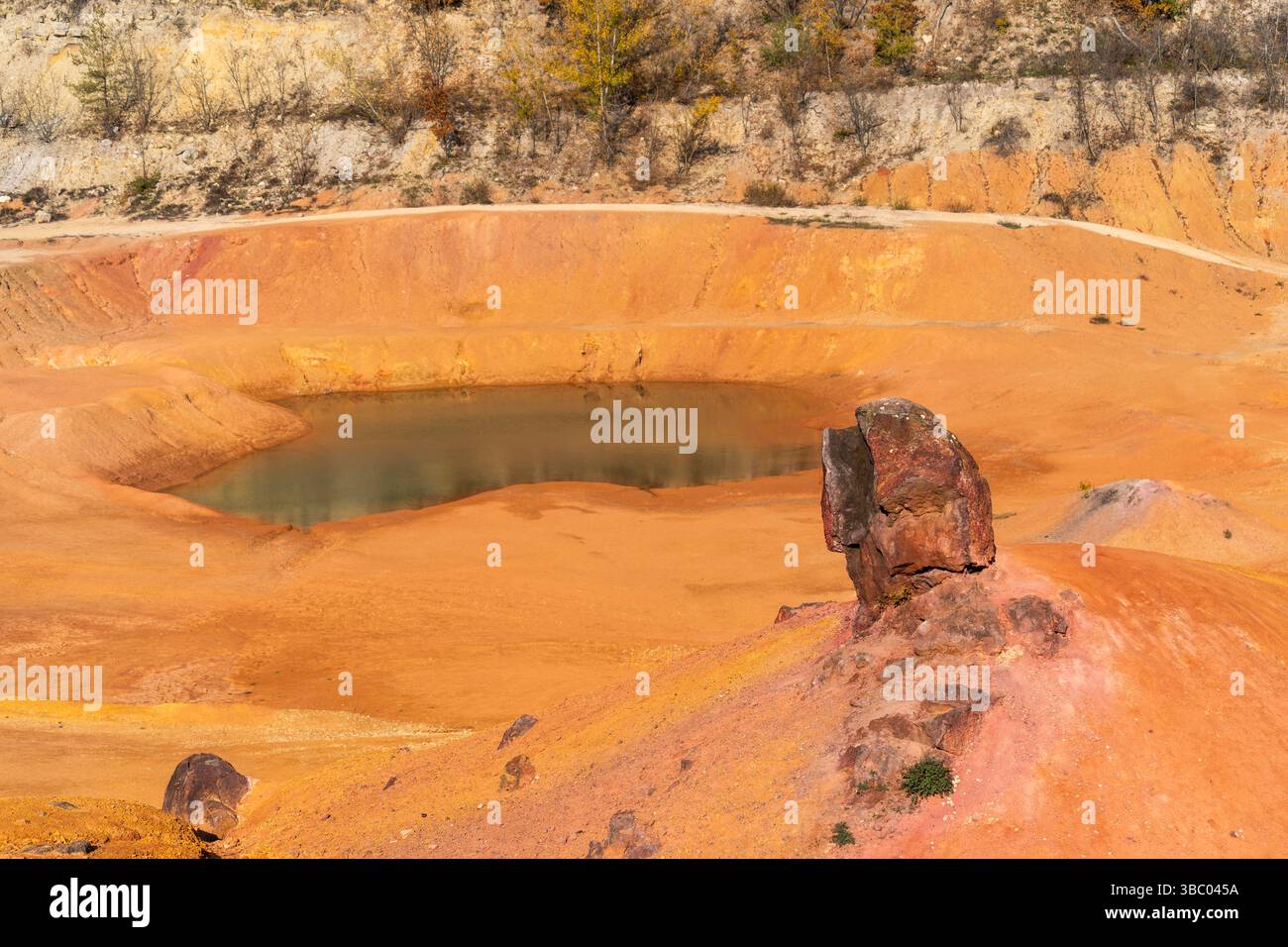 Eroded bauxite rock formation with bright orange colors in an abandoned ...