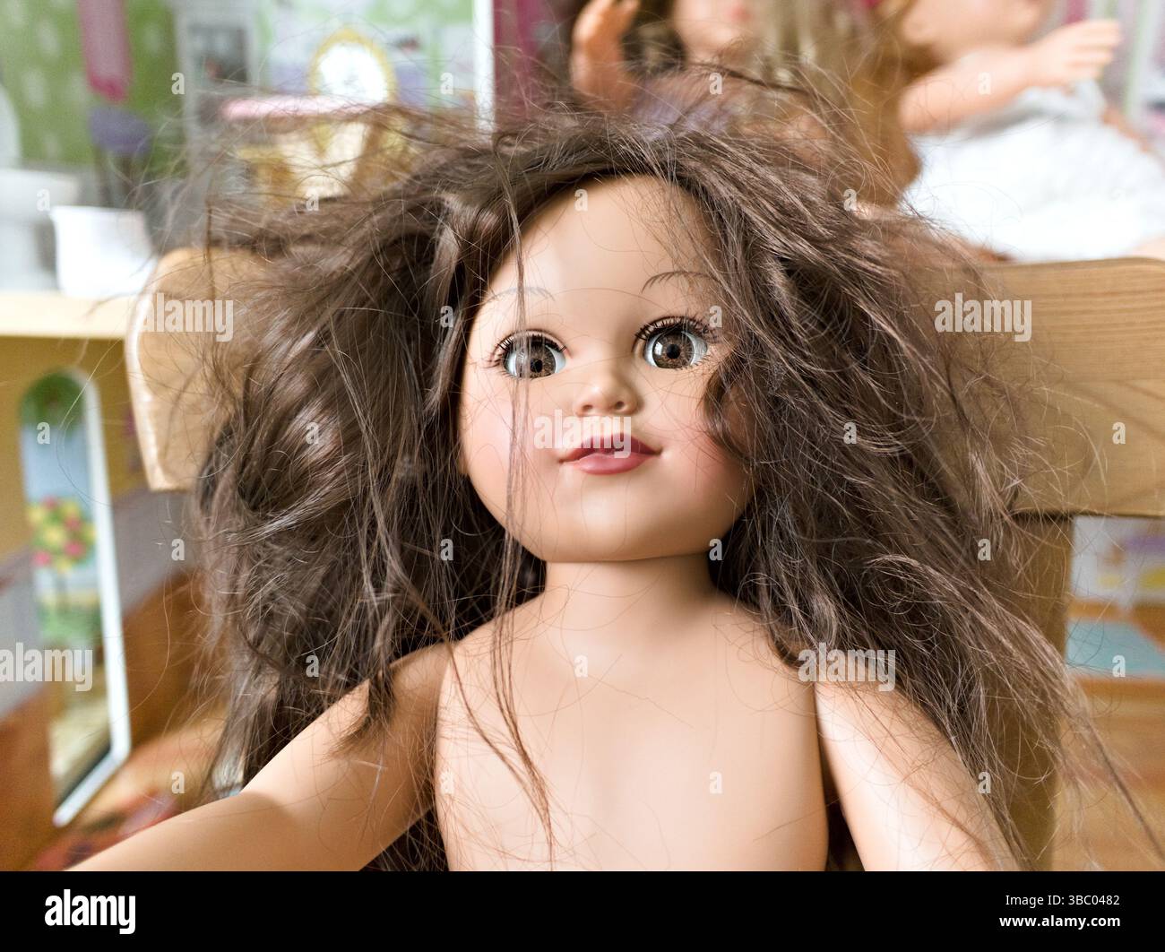 A doll with long brown hair is sitting on a table. The doll's hair is ...
