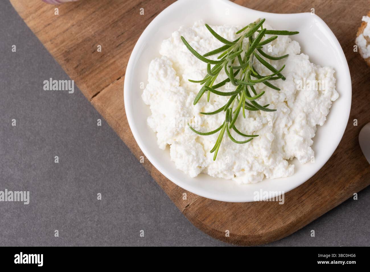 Creamy cottage cheese with fresh rosemary on a wooden tabletop Stock ...