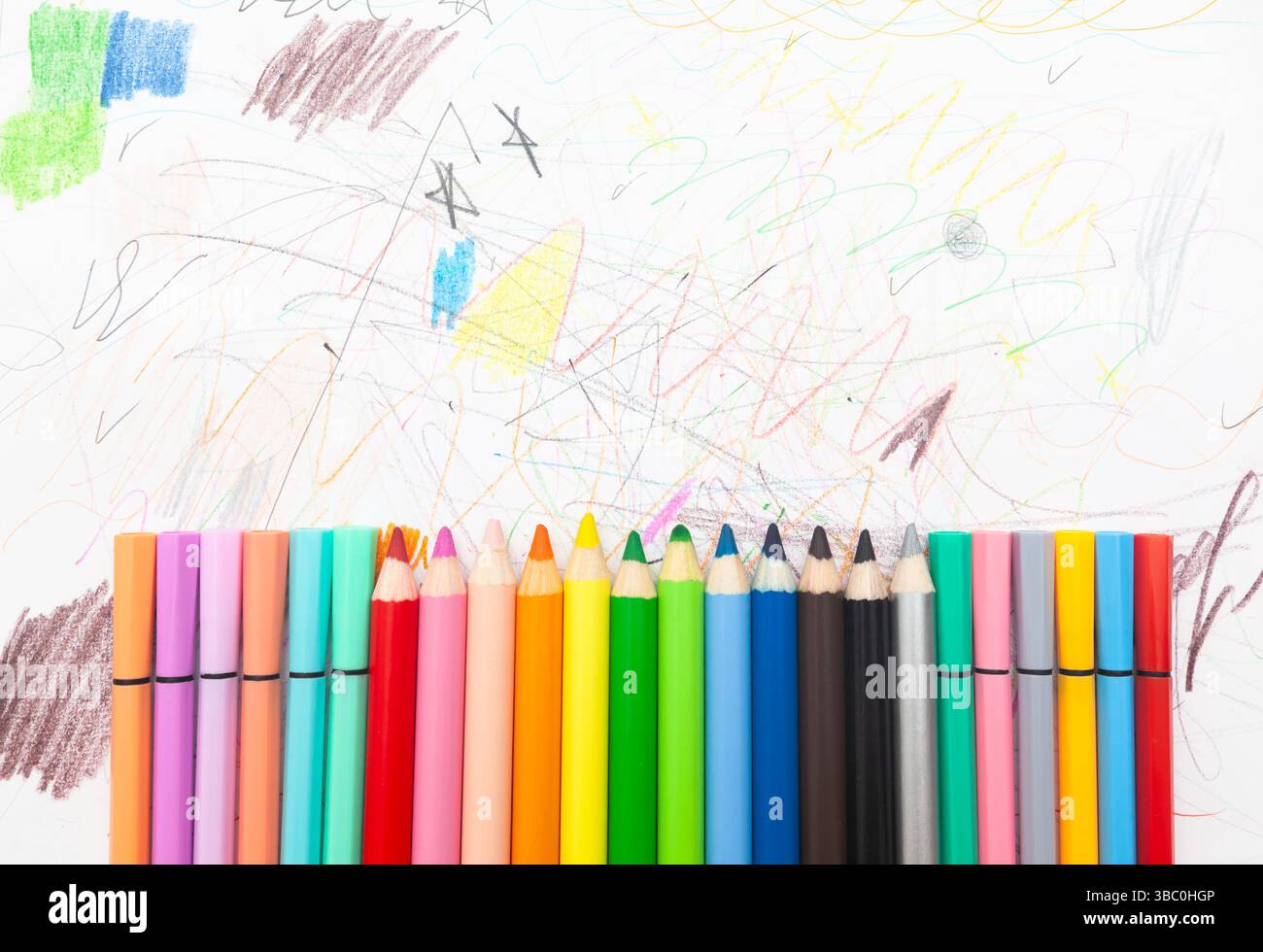Multi-colored pencils lie on white paper drawn with multi-colored ...