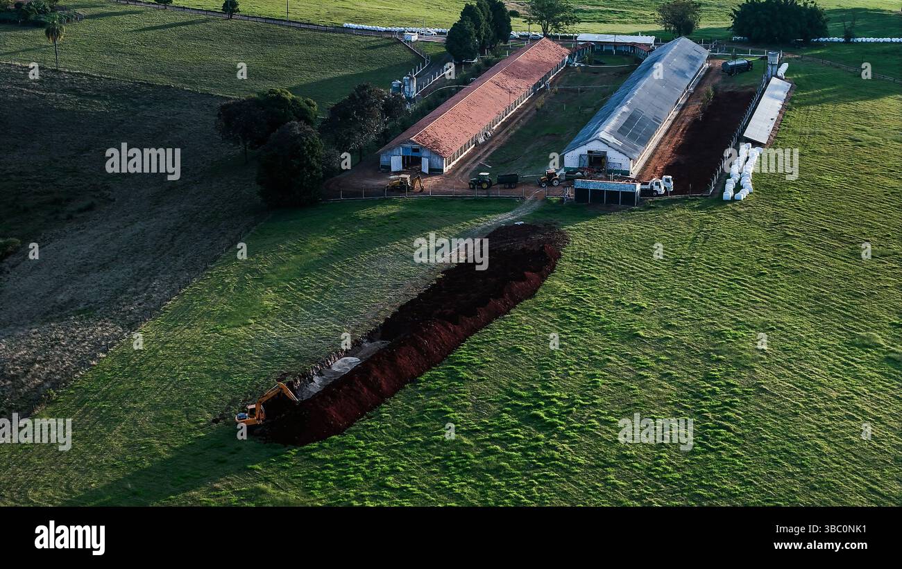An aerial view of an an excavator digging a trench to bury infected ...