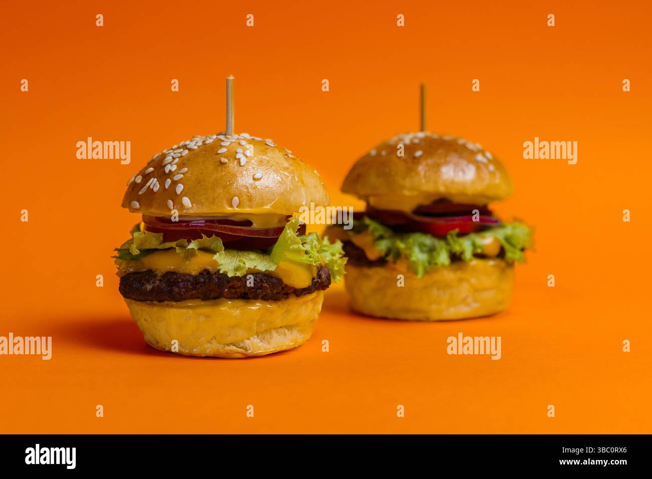 Two mini cheeseburgers on a vibrant background Stock Photo - Alamy
