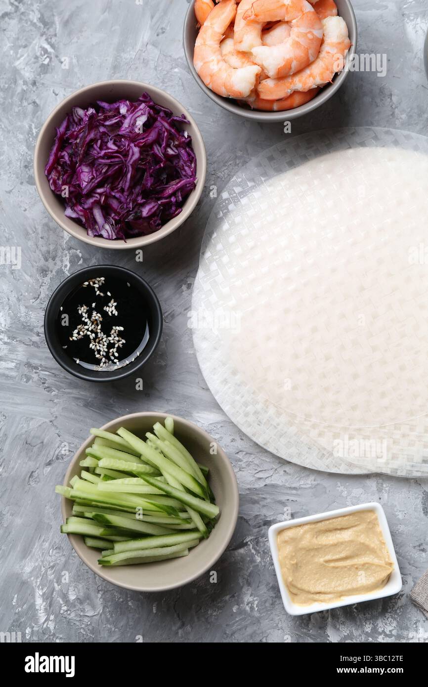 Rice paper sheets and different ingredients on light grey table, flat ...