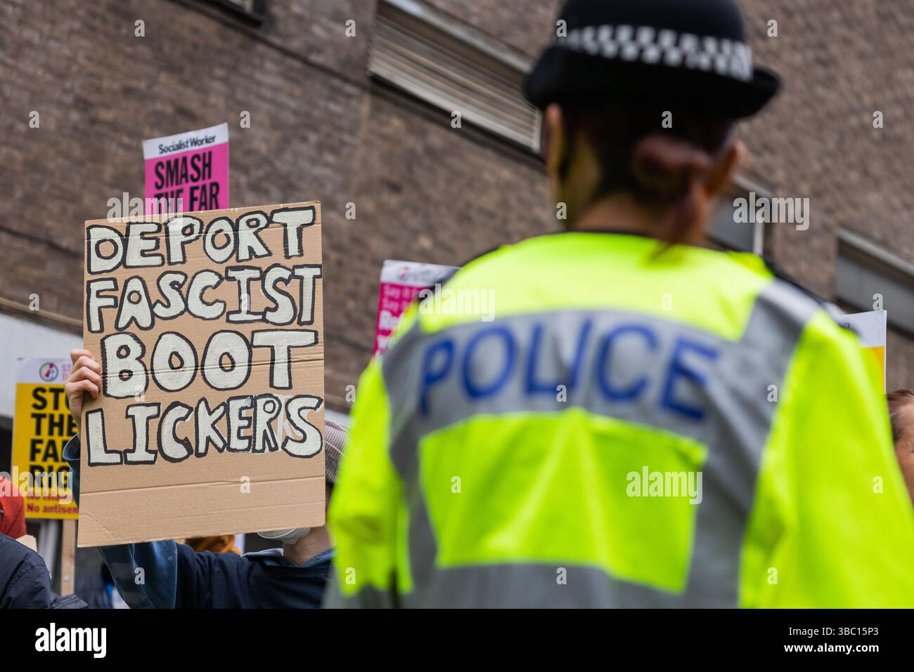 Birmingham, UK. 17 MAY, 2025. Police officer looks towards "Deport ...