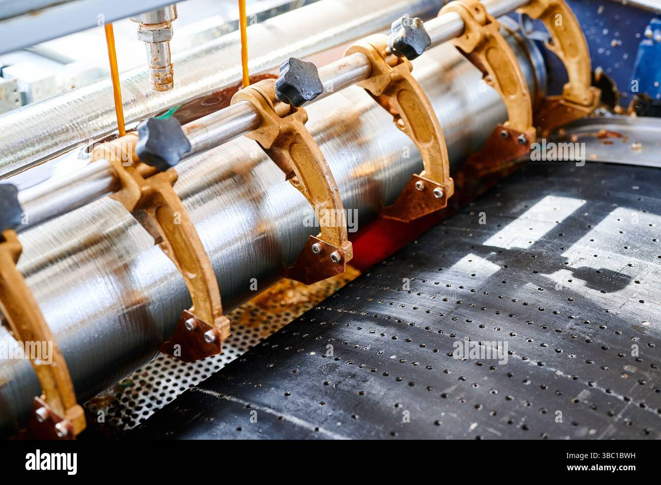 Rollers spreading adhesive in a bustling cardboard box manufacturing ...