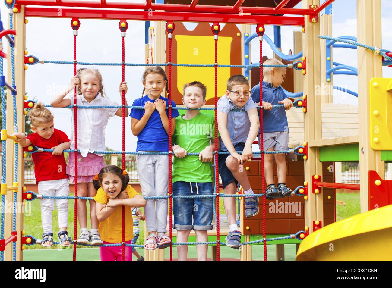 Happy children spending time climbing on rope net while break time at ...