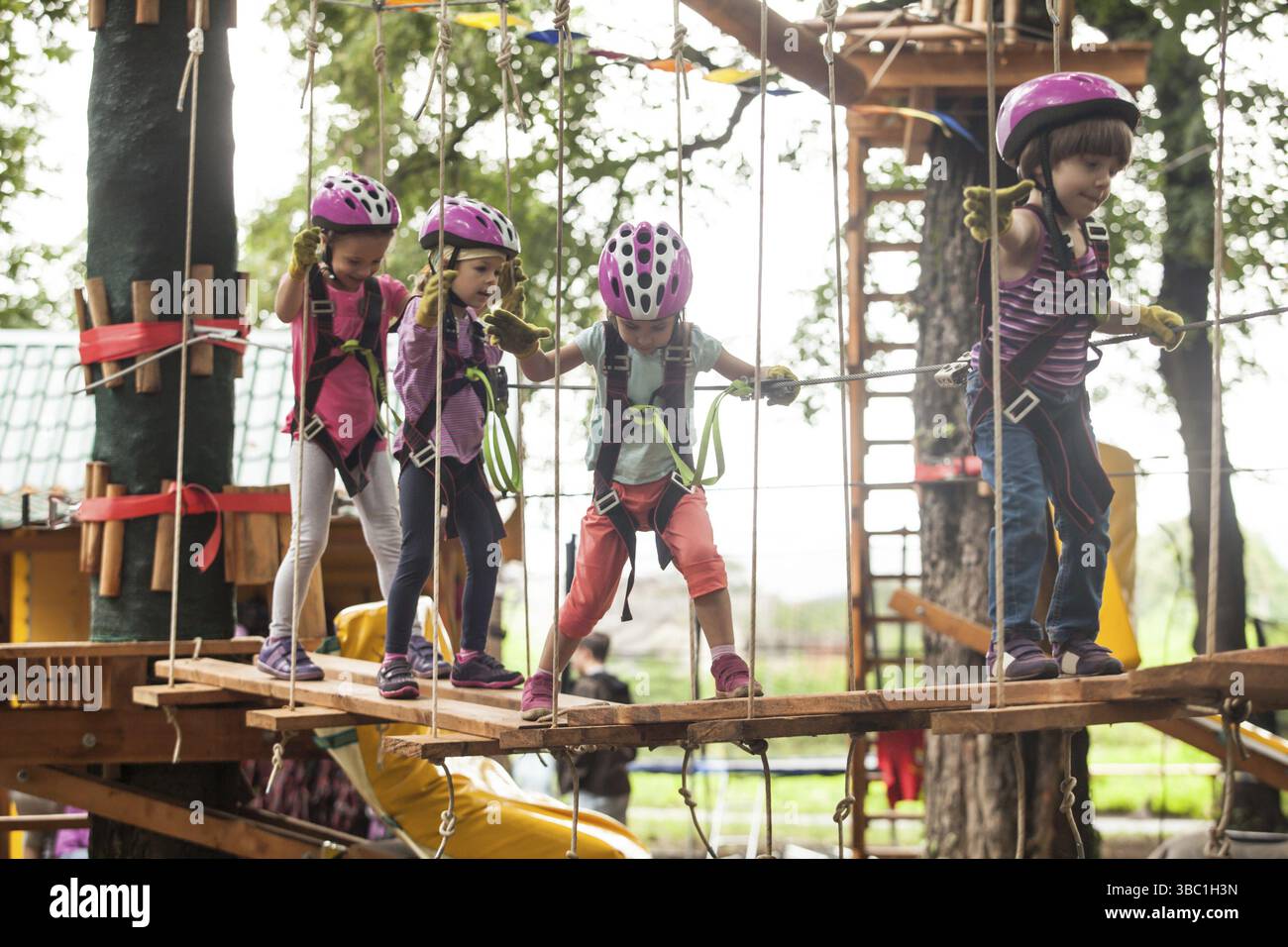 Kids on obstacle course in adventure park in mountain helmet and safety ...