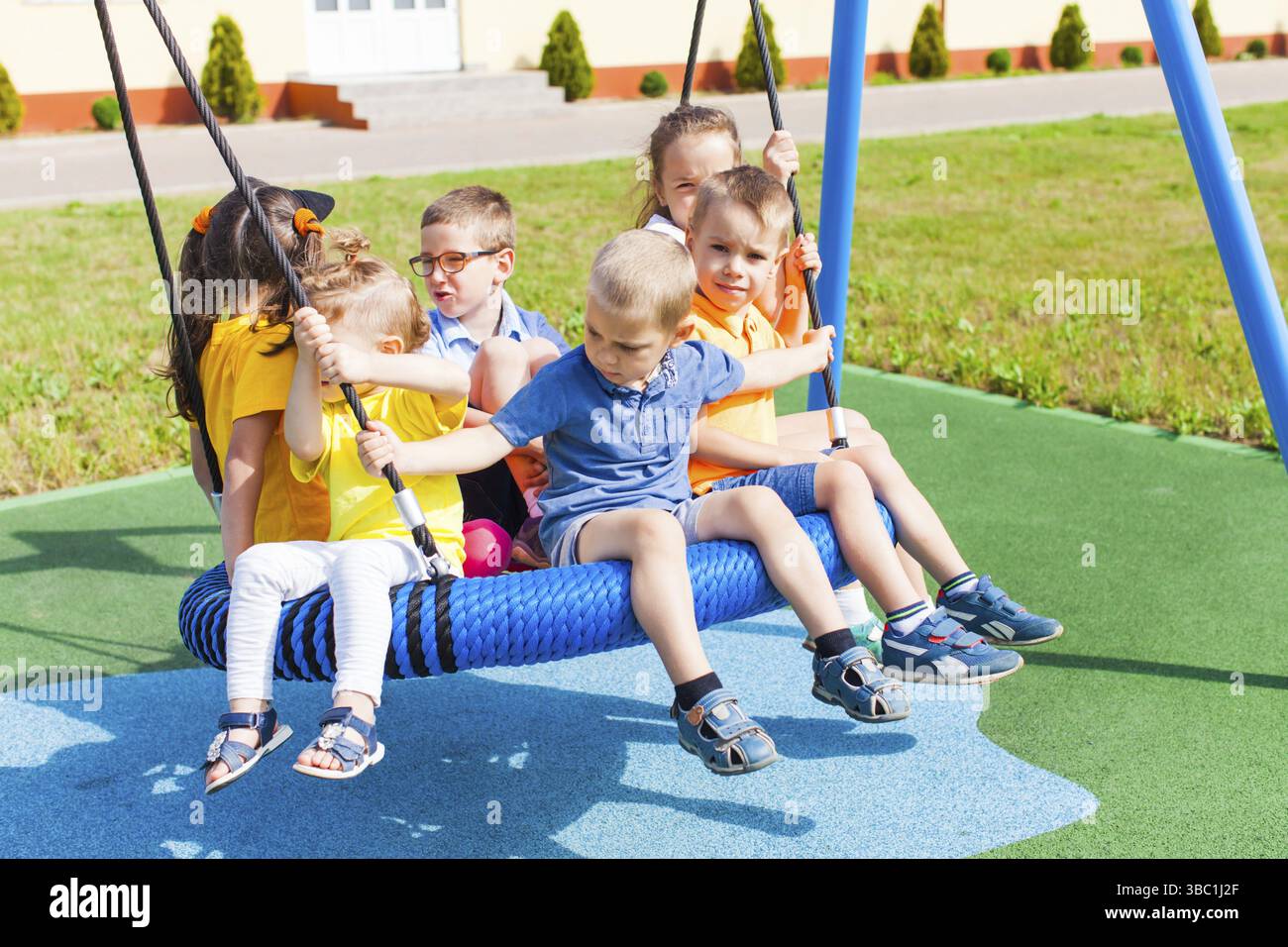 Cute boys and girls swinging on the spider web nest swing near the ...