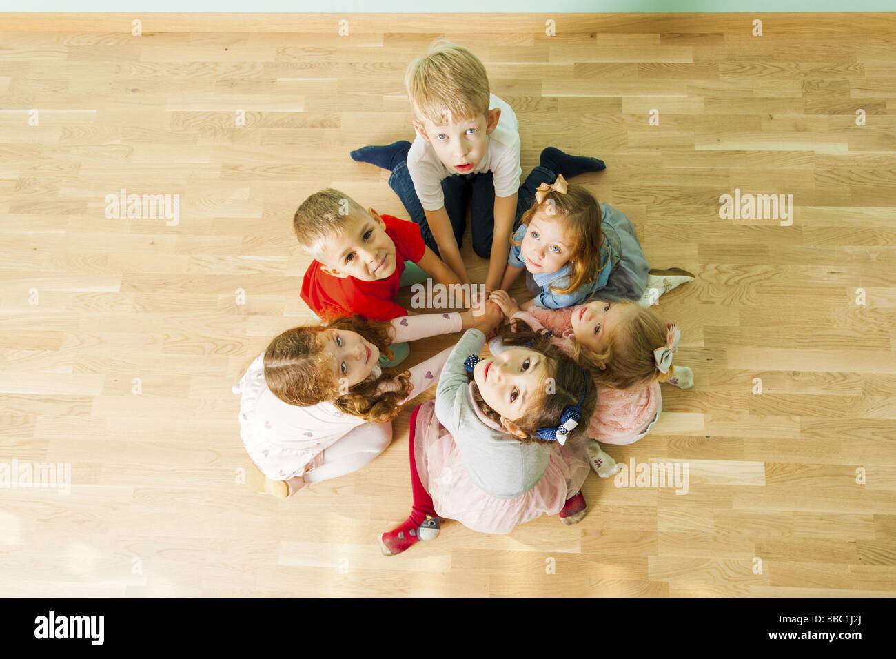 Curious and happy kids looking up at the camera sitting closely in a ...