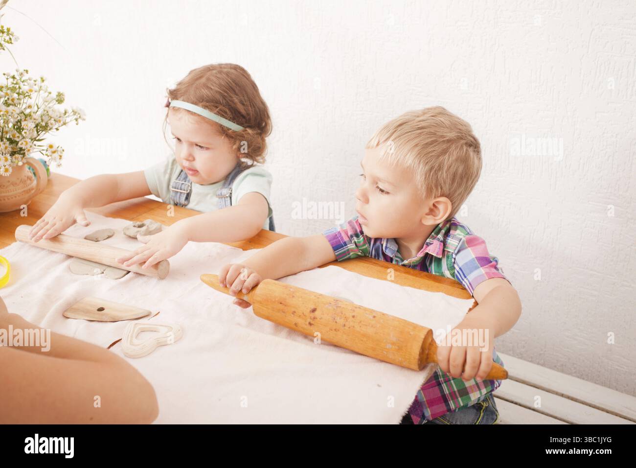 Little boy using a rolling pin that to roll modelling clay Stock Photo ...