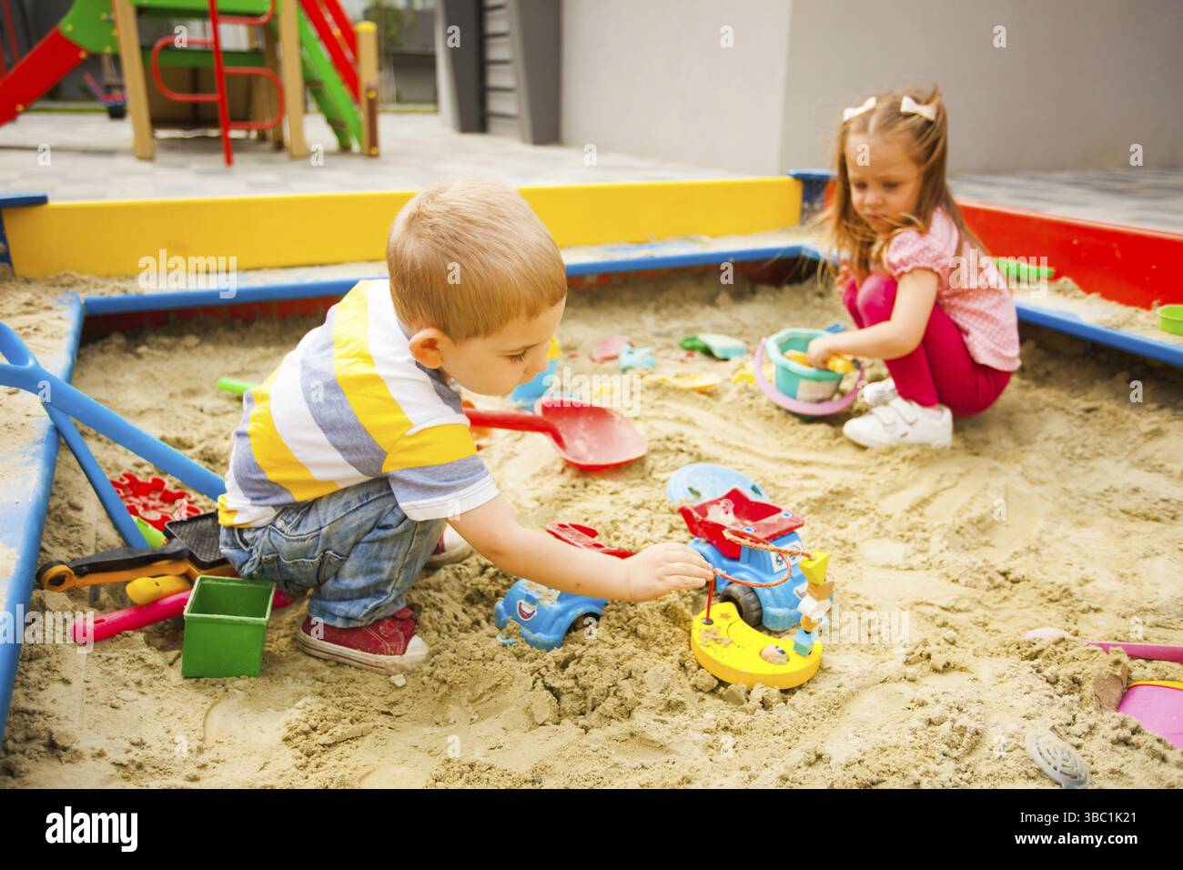 Happy children playing with sand at modern playground outside Stock ...