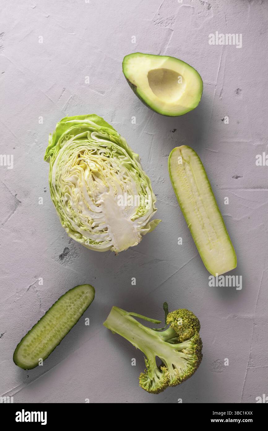 Composition of fresh green cut in half vegetables on a white background ...