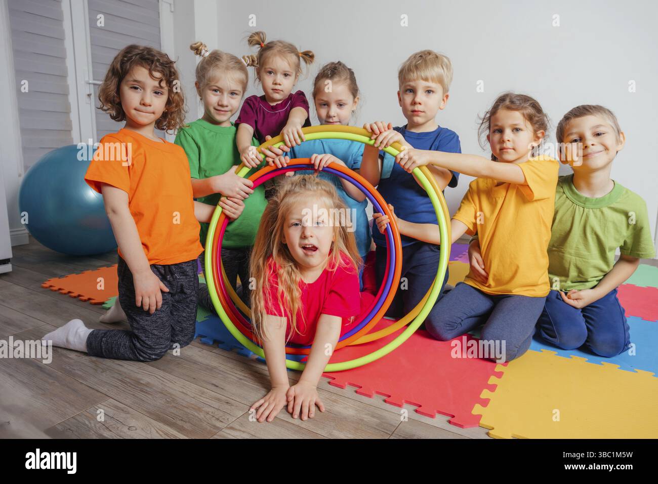 Group of cheerful kindergarten children in colrful t-shirts holding few ...