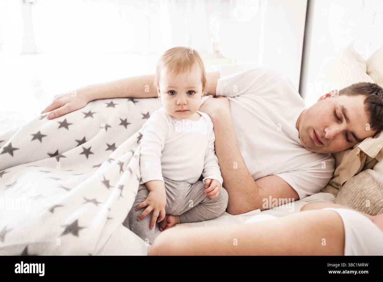 Tired and sleepy parents in the bed with her todler baby in the morning ...