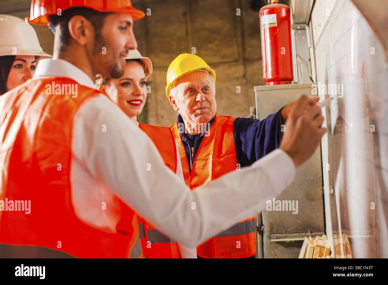 The group of workers in overalls are standing next by the flip chat ...