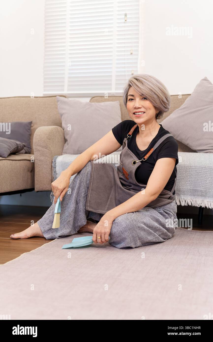 This image shows an older Asian woman smiling, wearing an apron, and ...