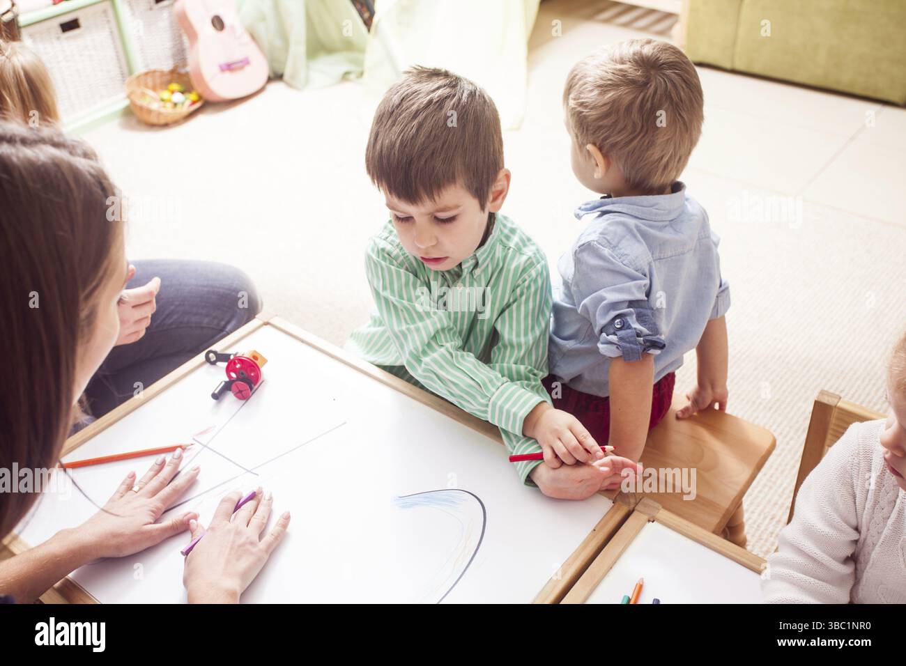 Overhead view of children in kindergarten learn letters and shapes ...