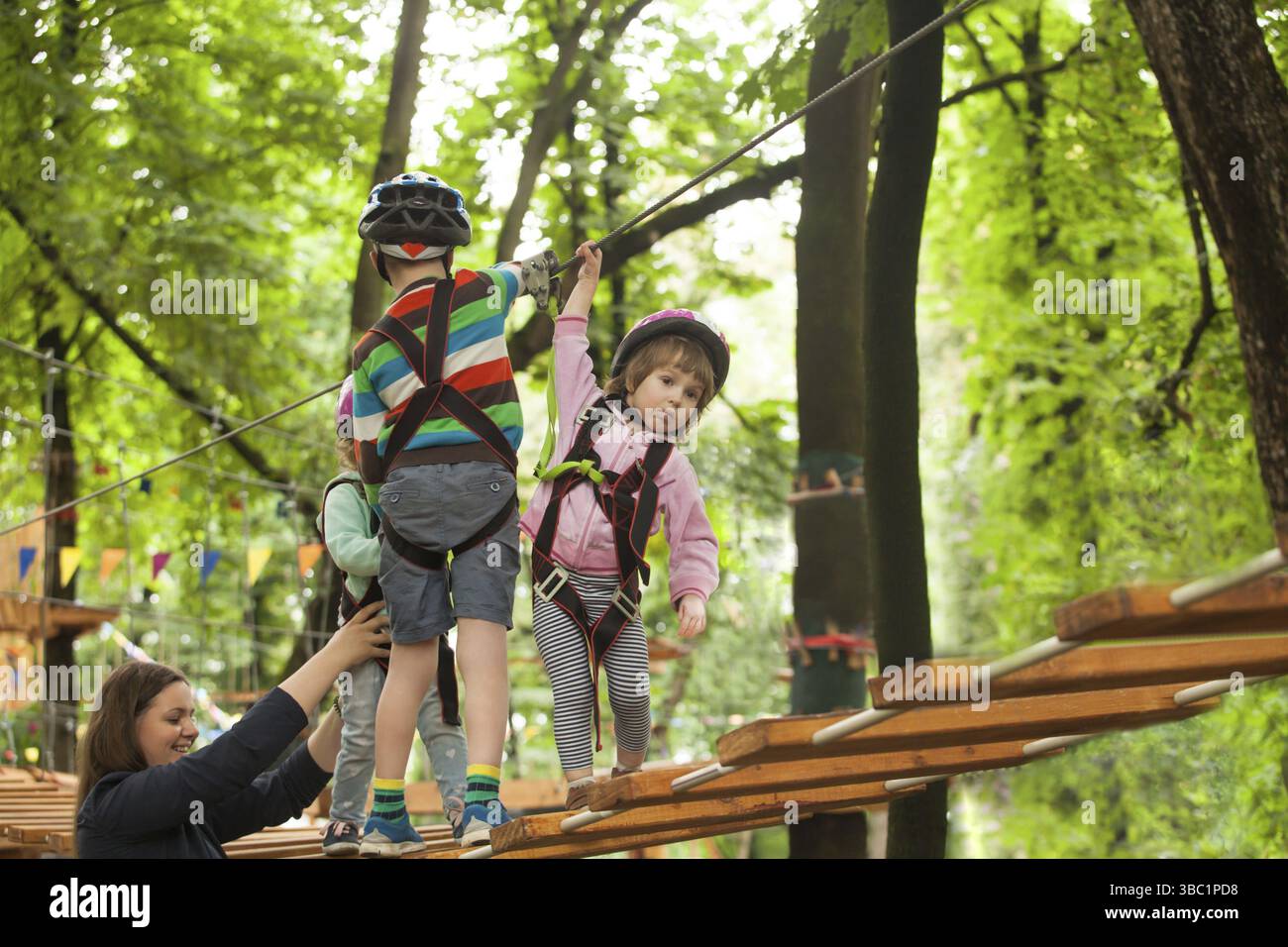 Group of children in a helmet and safety equipment in adventure ropes ...