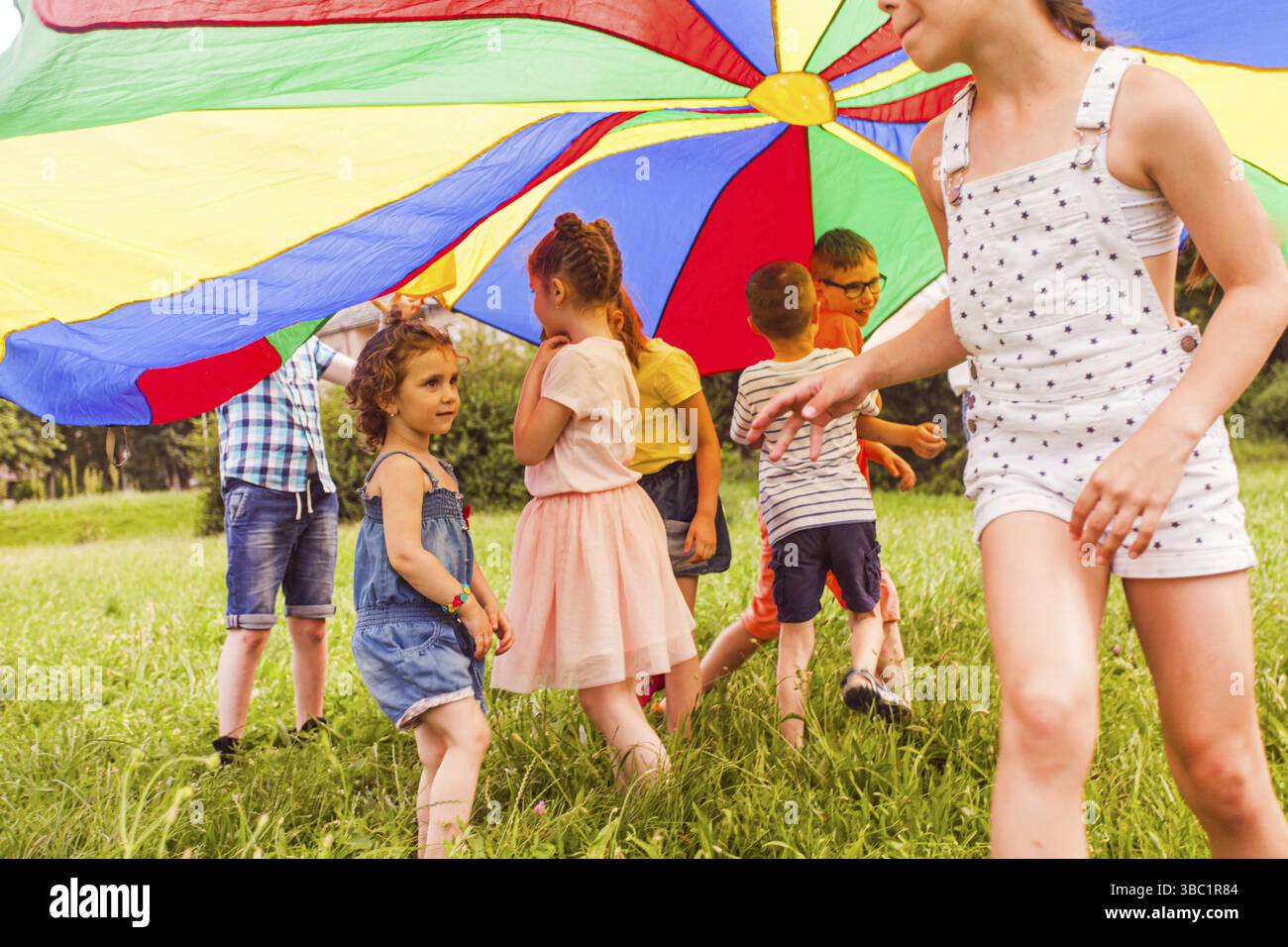 Portrait of adorable little girl standing unsure, trying to join active ...
