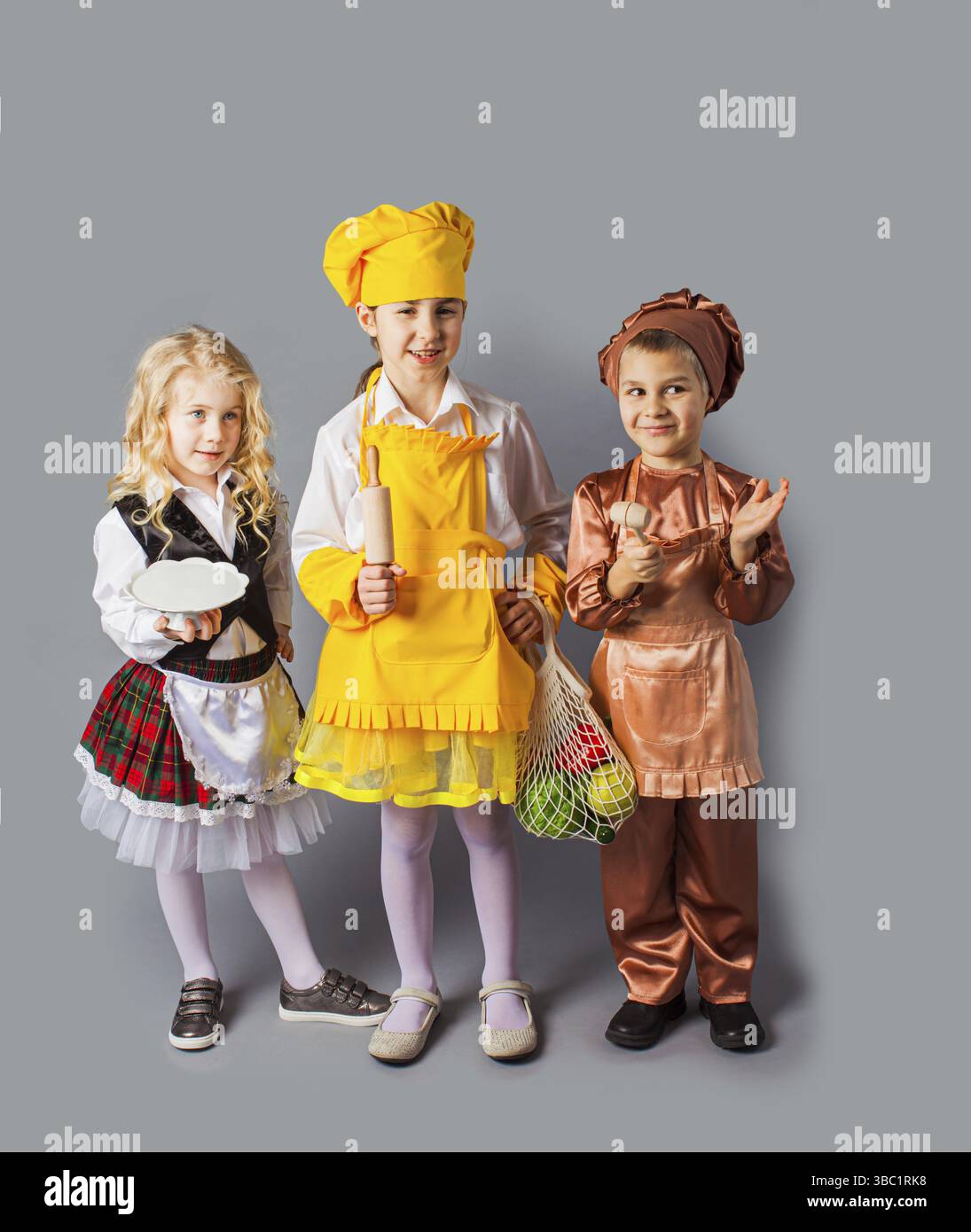 Three happy preschool children are posing at the gray background. The ...