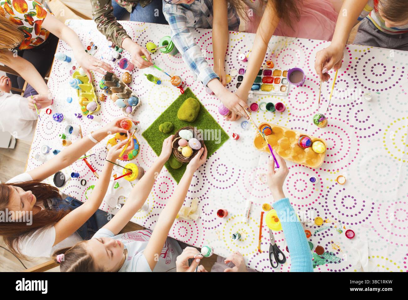 Top view of kids hands holding Easter crafts and colored eggs. Group of ...