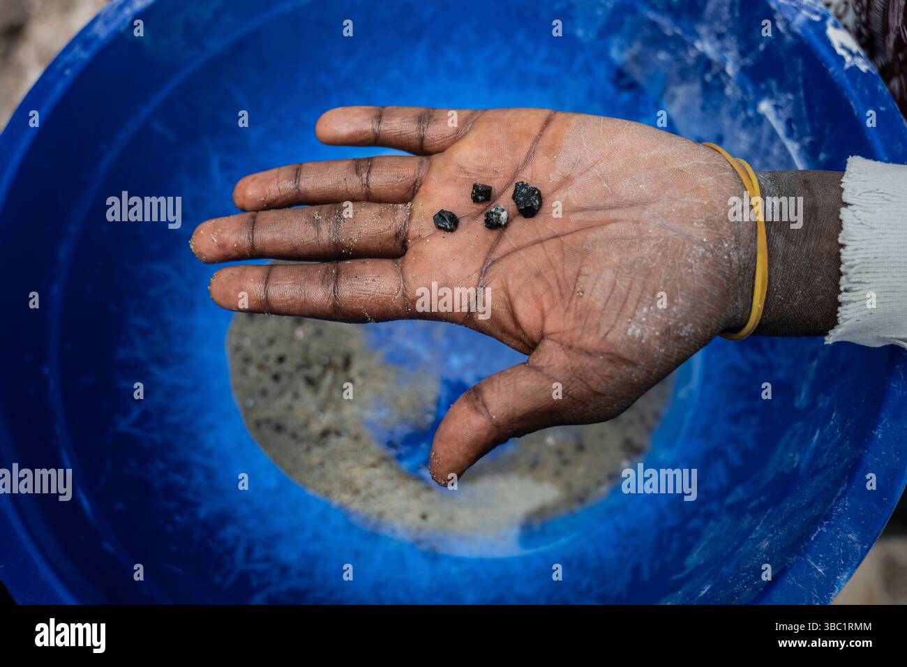 A mine worker holds bits of coltan ore in the mining town of Rubaya ...