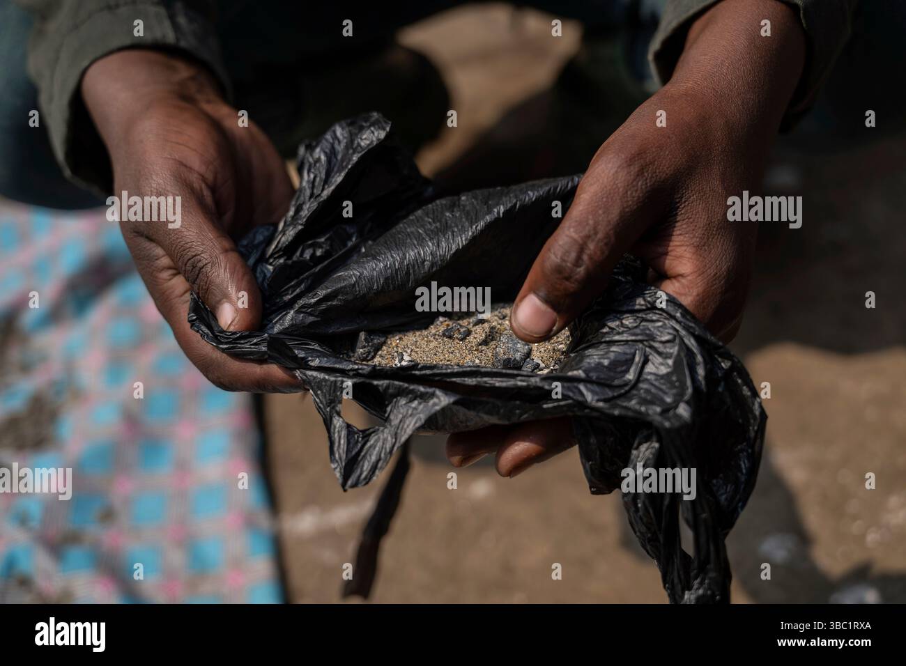 A miner holds newly extracted coltan ore in Rubaya, Democratic Republic ...