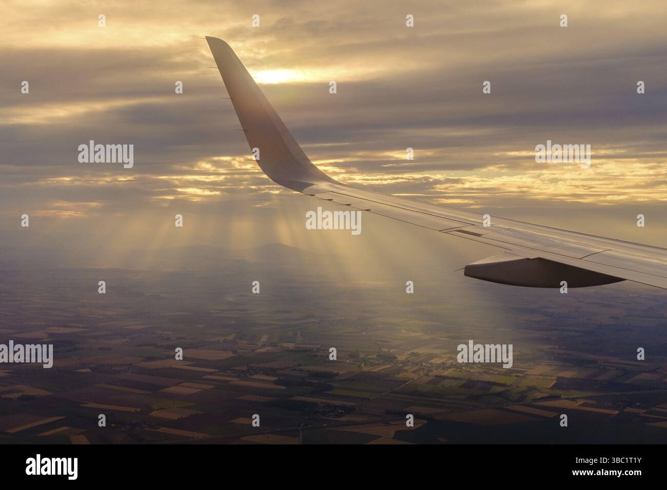 Wing of the plane during the flight with sun rays in the background ...