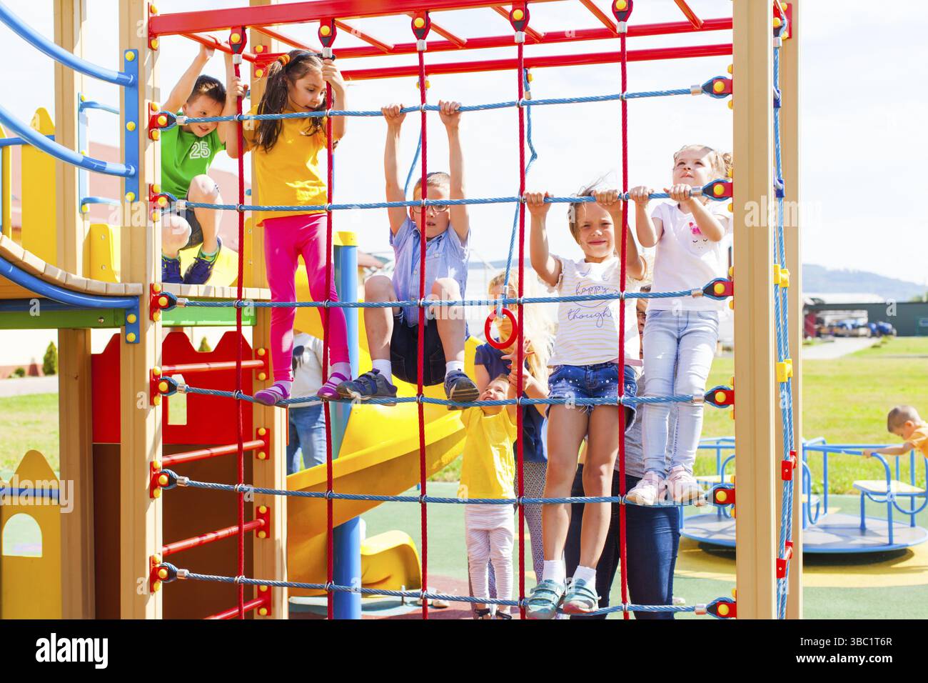 Many kids with moms, have fun on the playground Stock Photo - Alamy
