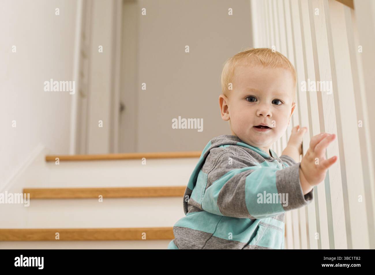 Portrait of lovely blond toddler boy in stripped sweatshot, holding ...
