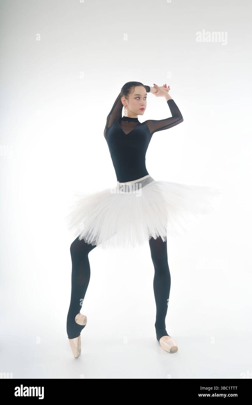 A young ballerina in a black leotard and tutu shows an eversion of her ...