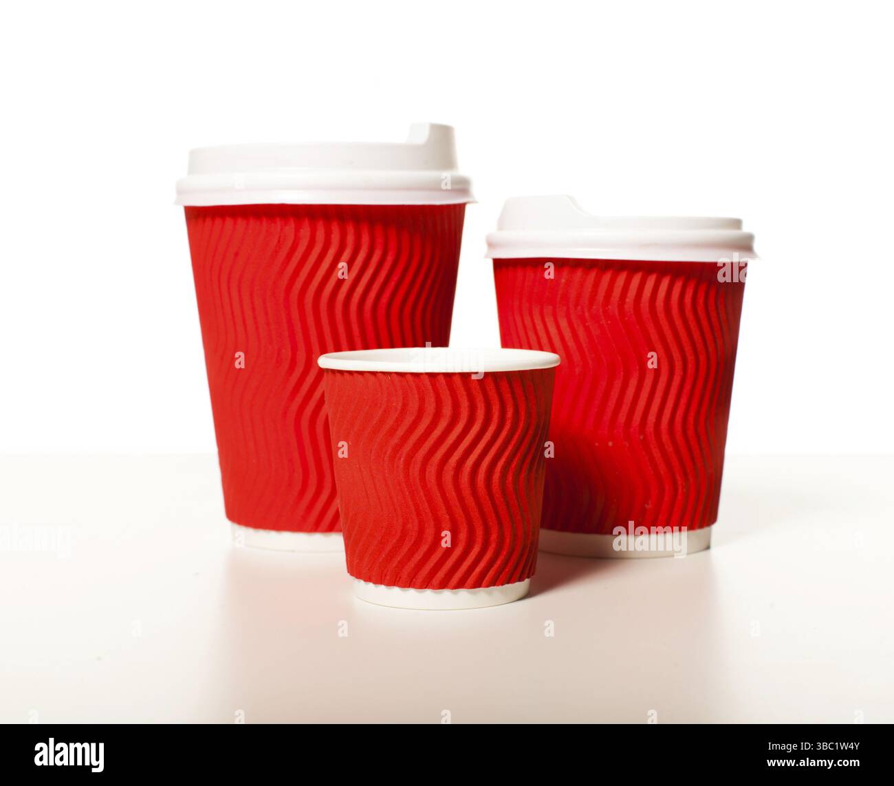 Disposable red paper coffee cups of different sizes standing in a row ...