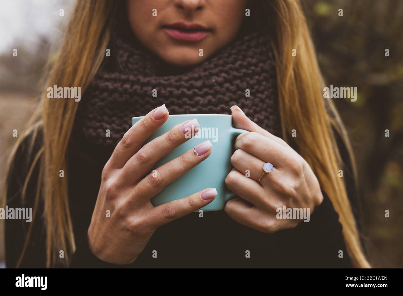 Female hands with tender pink nail design holding blue cup outdoors ...
