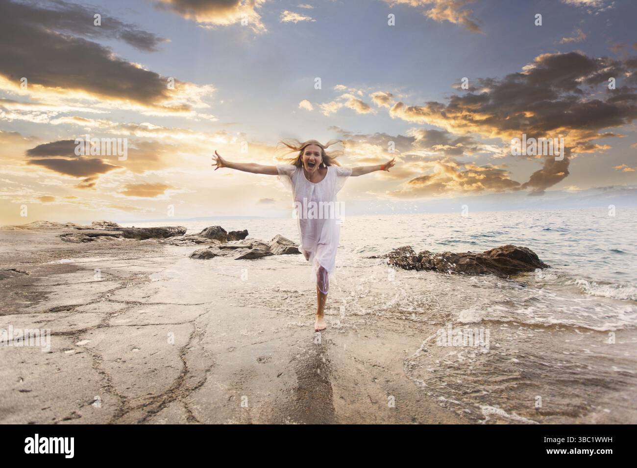 The beautiful woman in a light summer dress with hands open walking ...