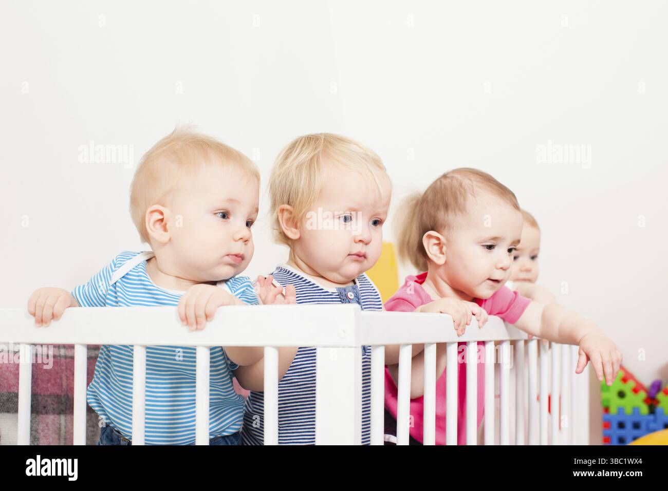 Group of little babies are stand up in the crib, day care center Stock ...