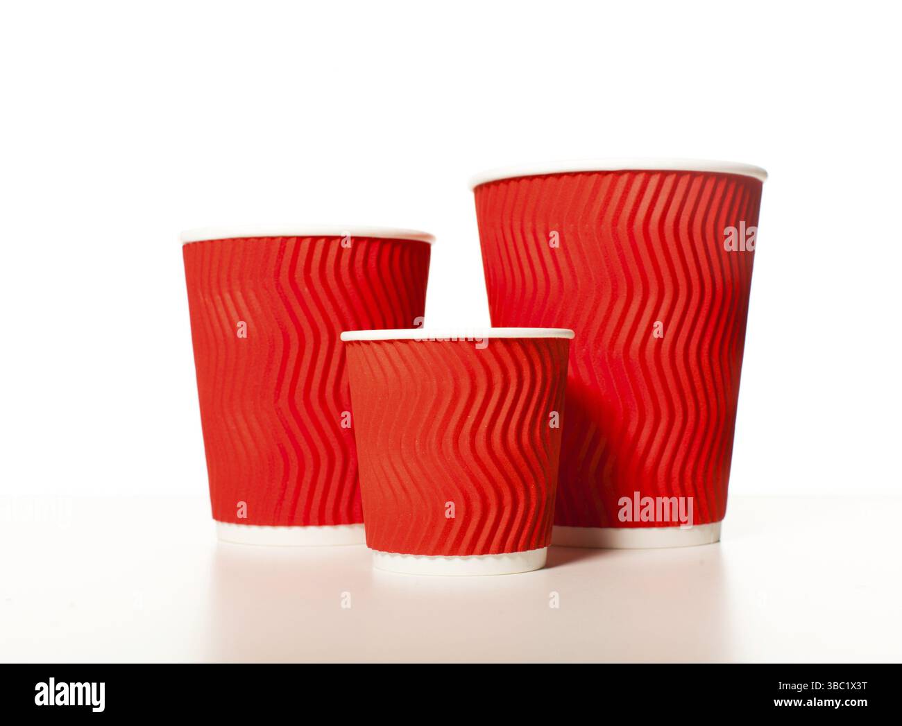 Disposable red paper coffee cups of different sizes standing in a row ...