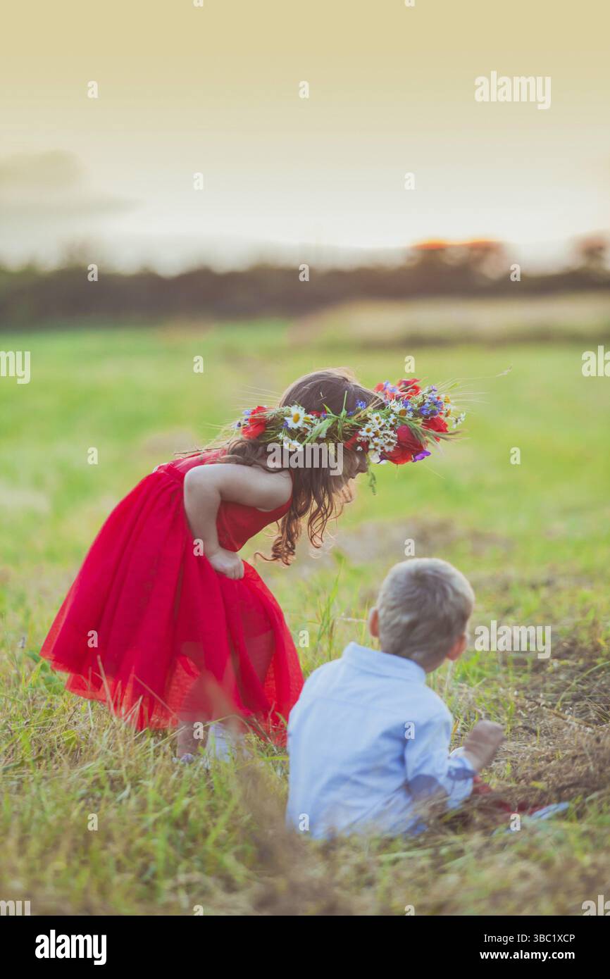 Cute girl is trying to put a floral wreath on her brother head Stock ...