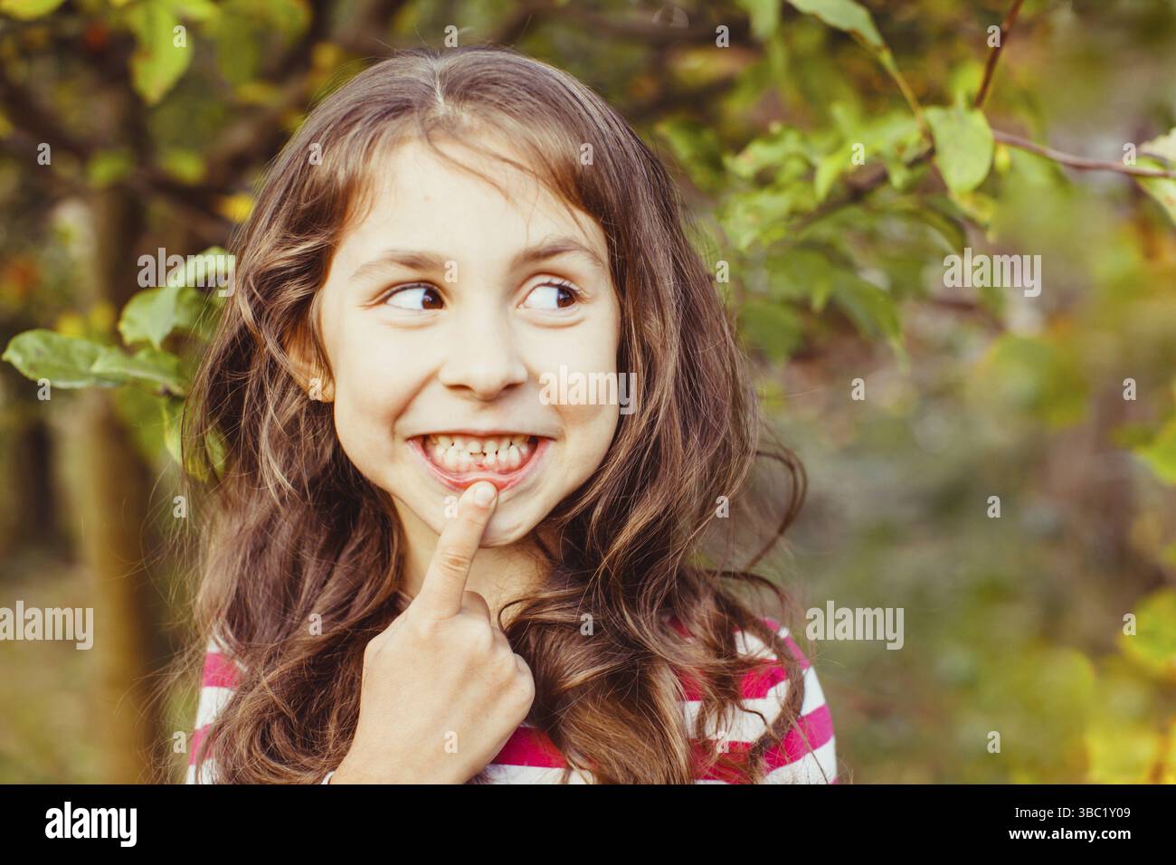 Beautiful child girl with long curly brown hair and brown eyes pointing ...