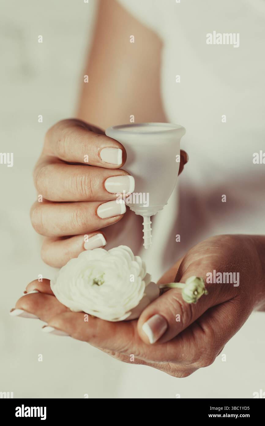 Menstrual cup in female hands. Woman holds flower and silicone hygiene ...