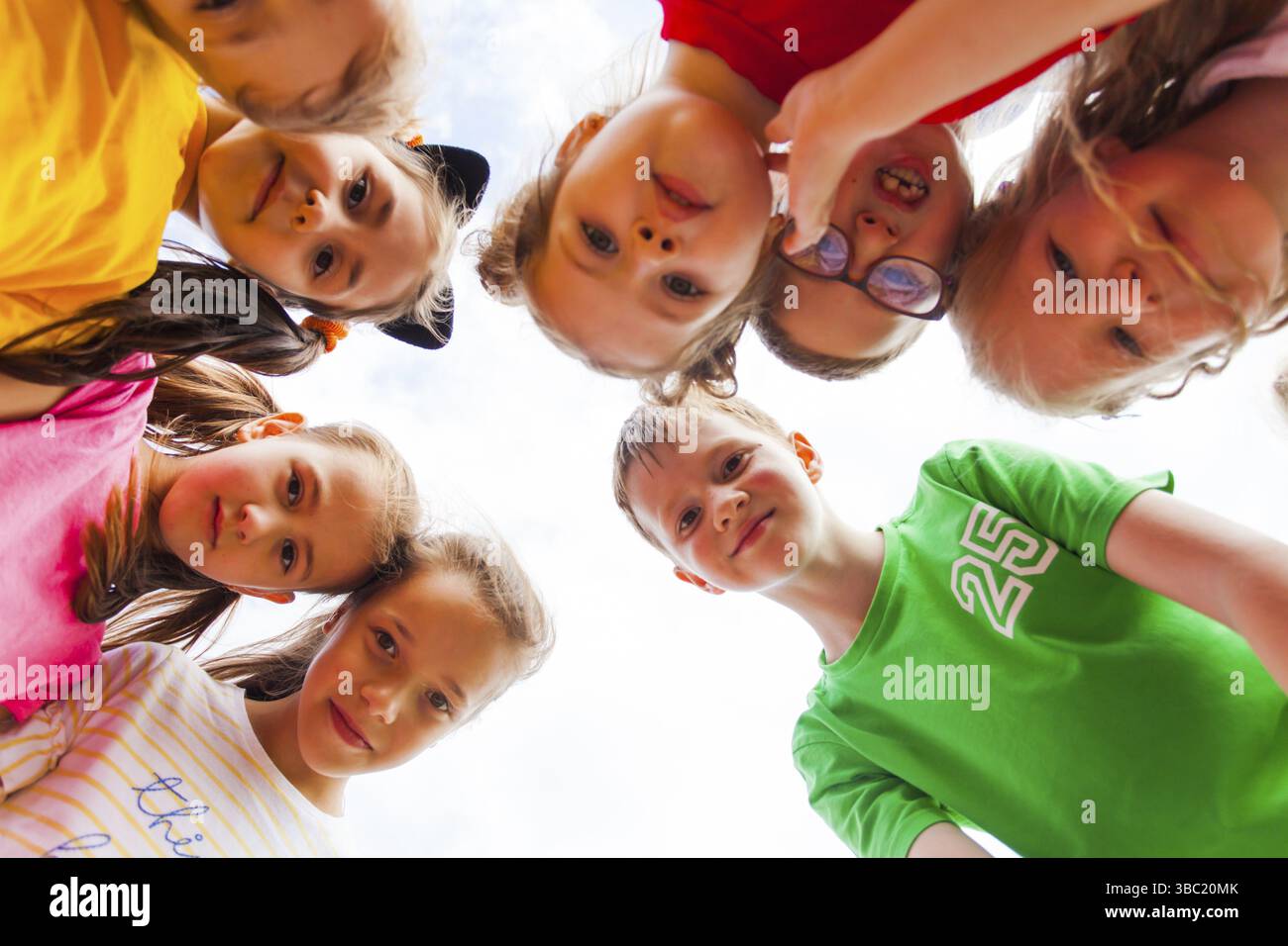 Close view of happy children faces in a circle, bottom view. Eight ...