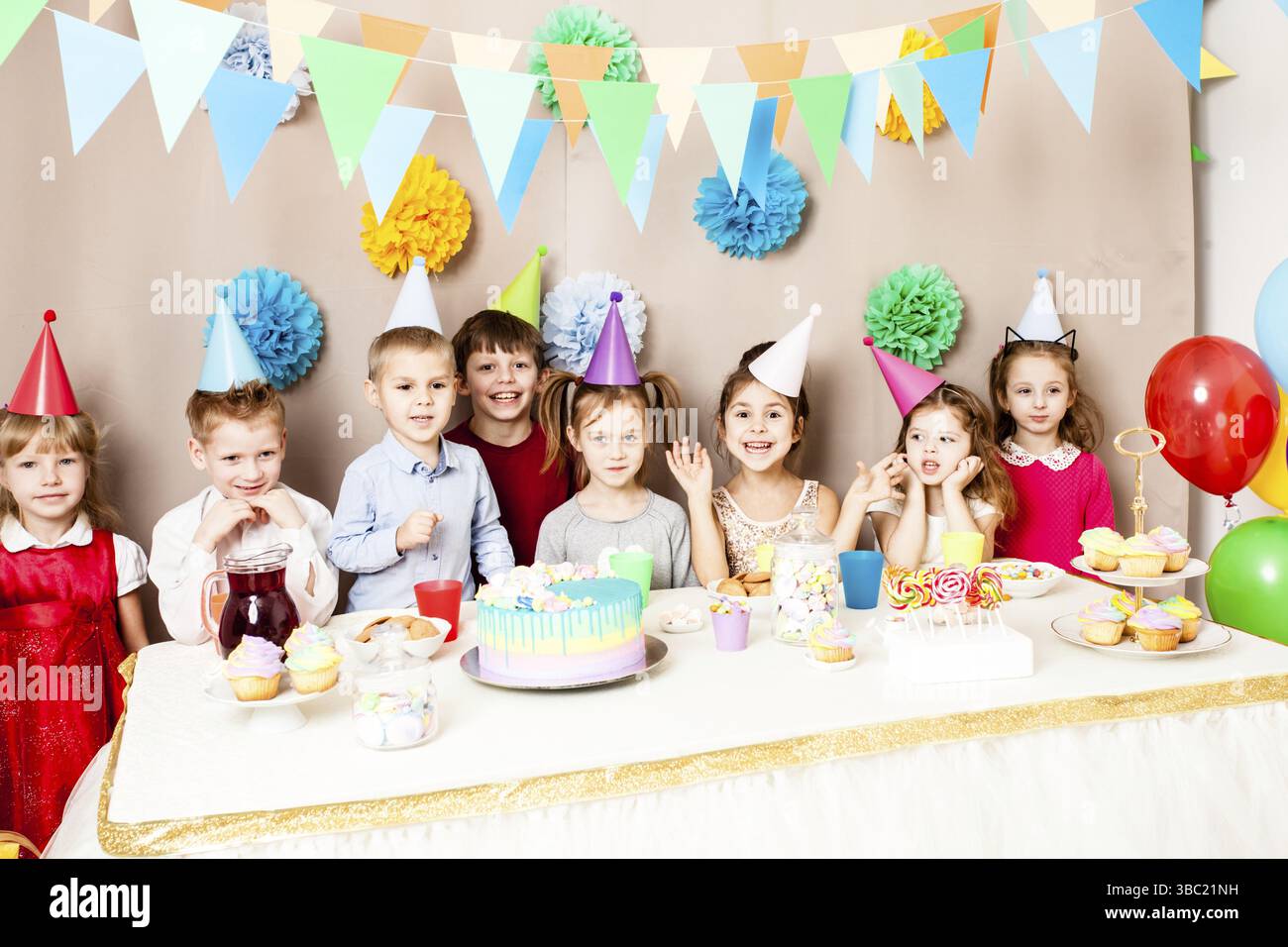 Little kids celebrating birthday. Many children near the table, friends ...